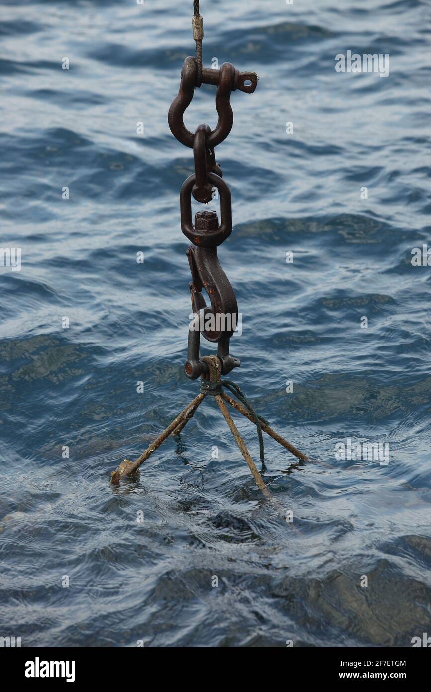 Object being raised with crane from the sea. Focus on the lifting hook ...