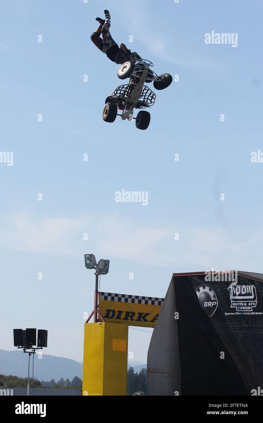 A person jumping with a quad bike high up in the sky and making a trick ...