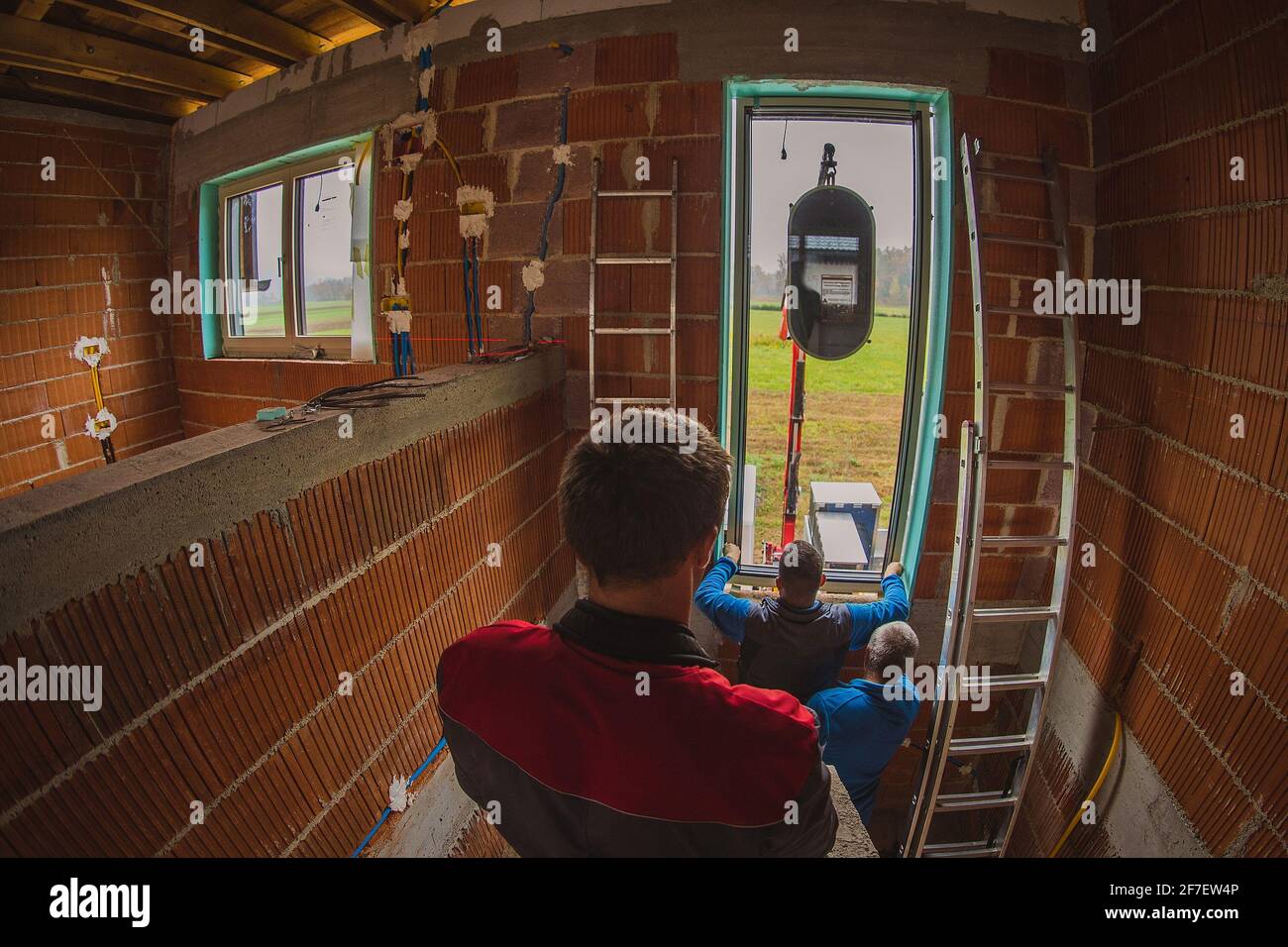 Three male workers installing a modern glass window into a new house ...
