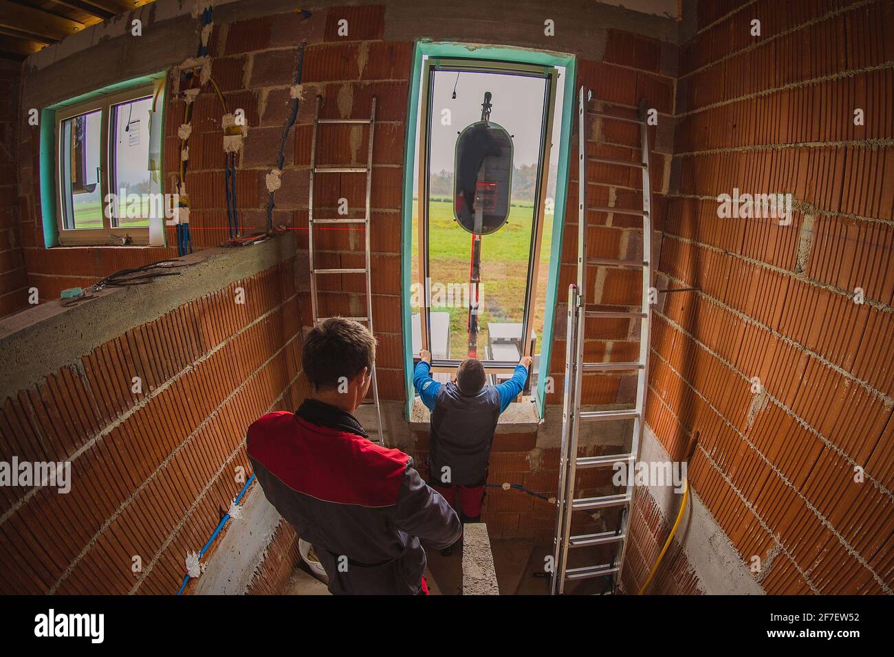 Two male workers installing a modern glass window into a new house ...