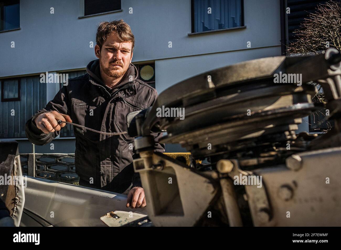 A young male is trying to start an outboard engine with pulling the ...