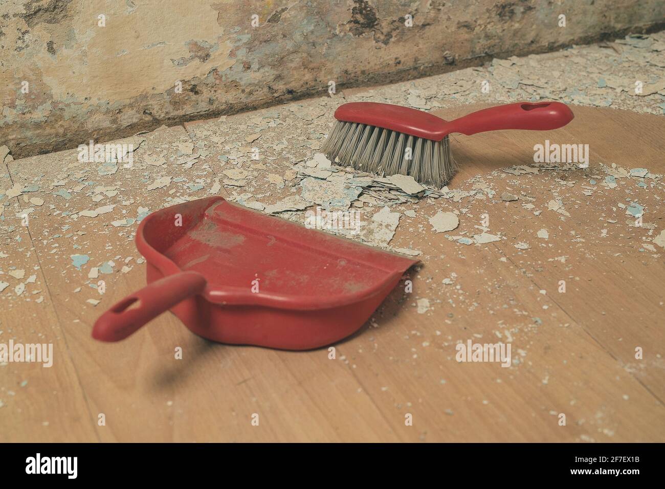 Red plastic broom sweeping away debris fallen from an old wet mossy ...