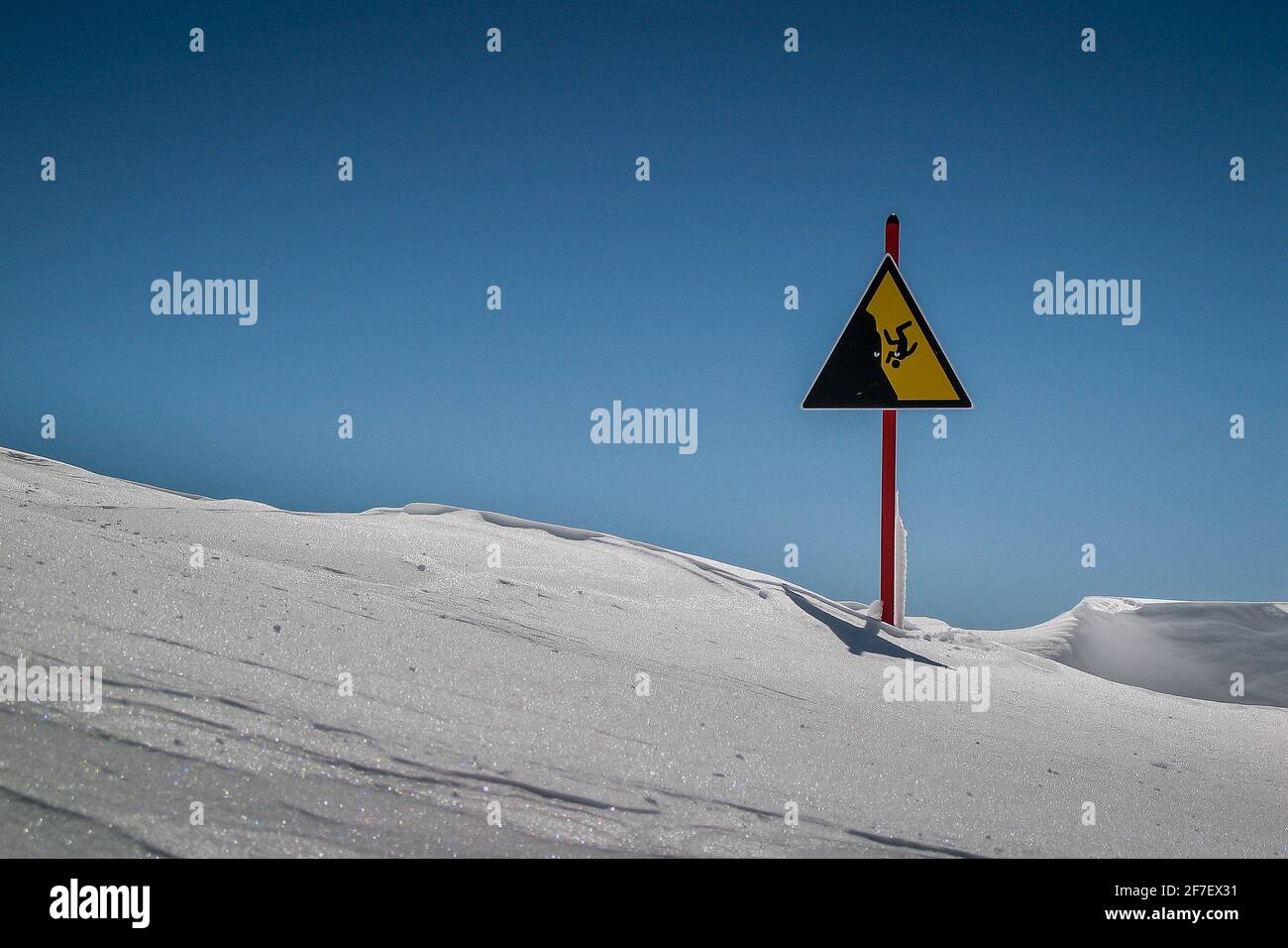 Warning sign for danger of falling down the cliff on the ski slope in ...