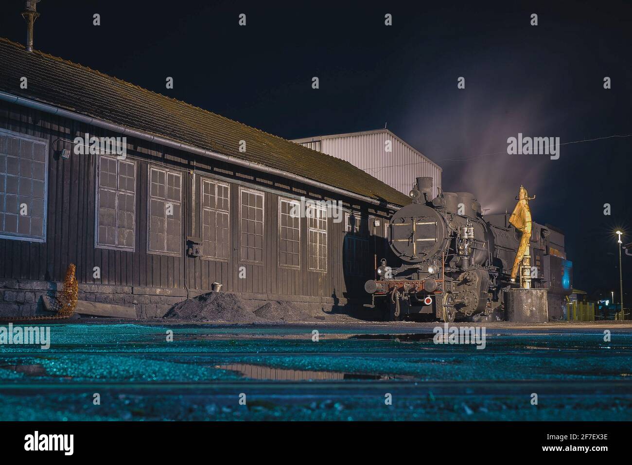 Old steam locomotive being fired up in front of a shed during the night ...