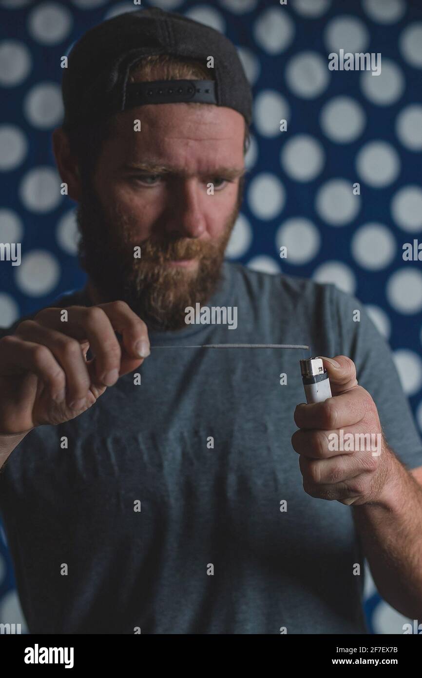 Hipster looking man with beard trying to light up a straw with a ...