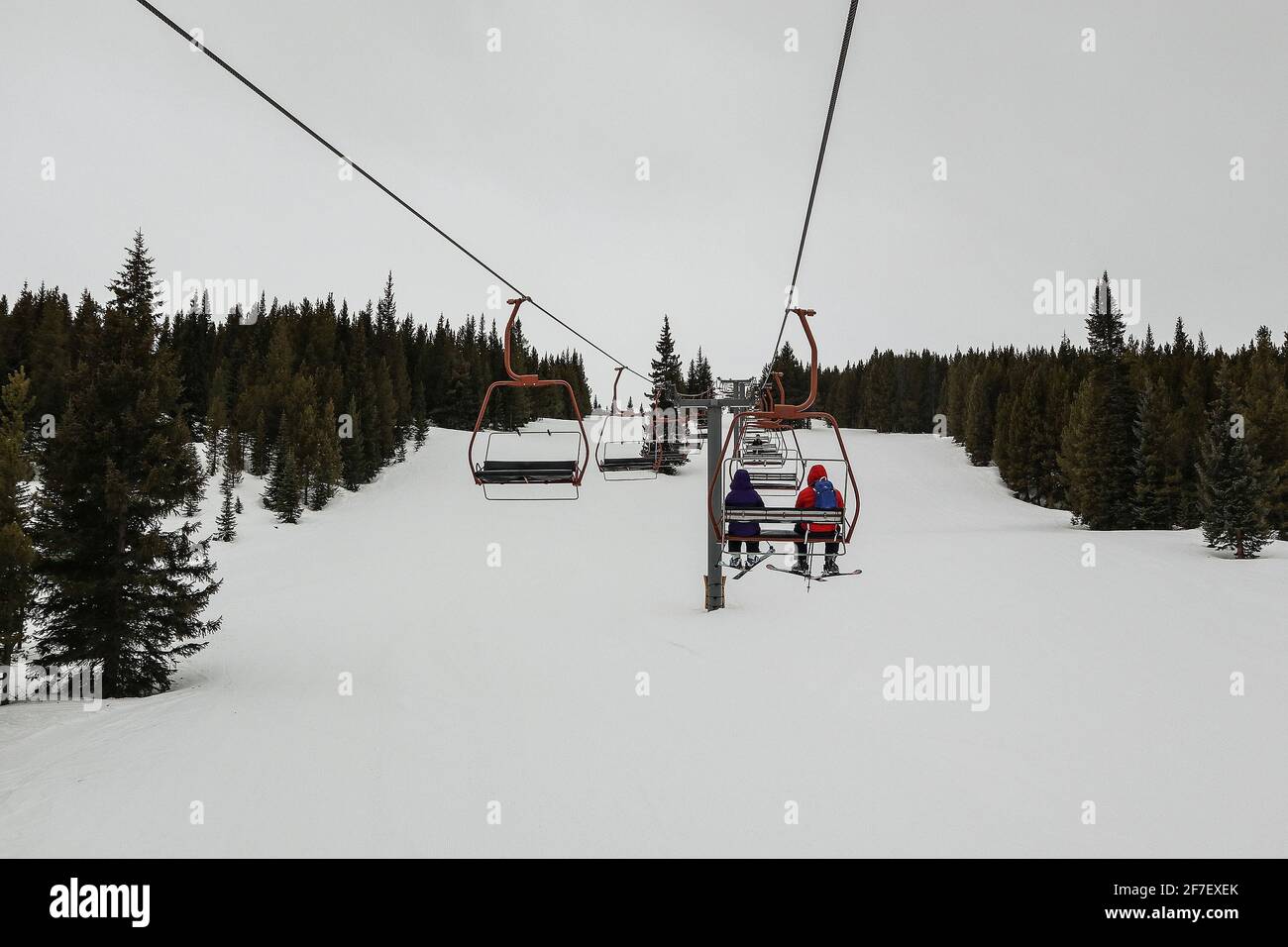 Chair lift on Copper mountain in a cloudy weather. Trees and some ...