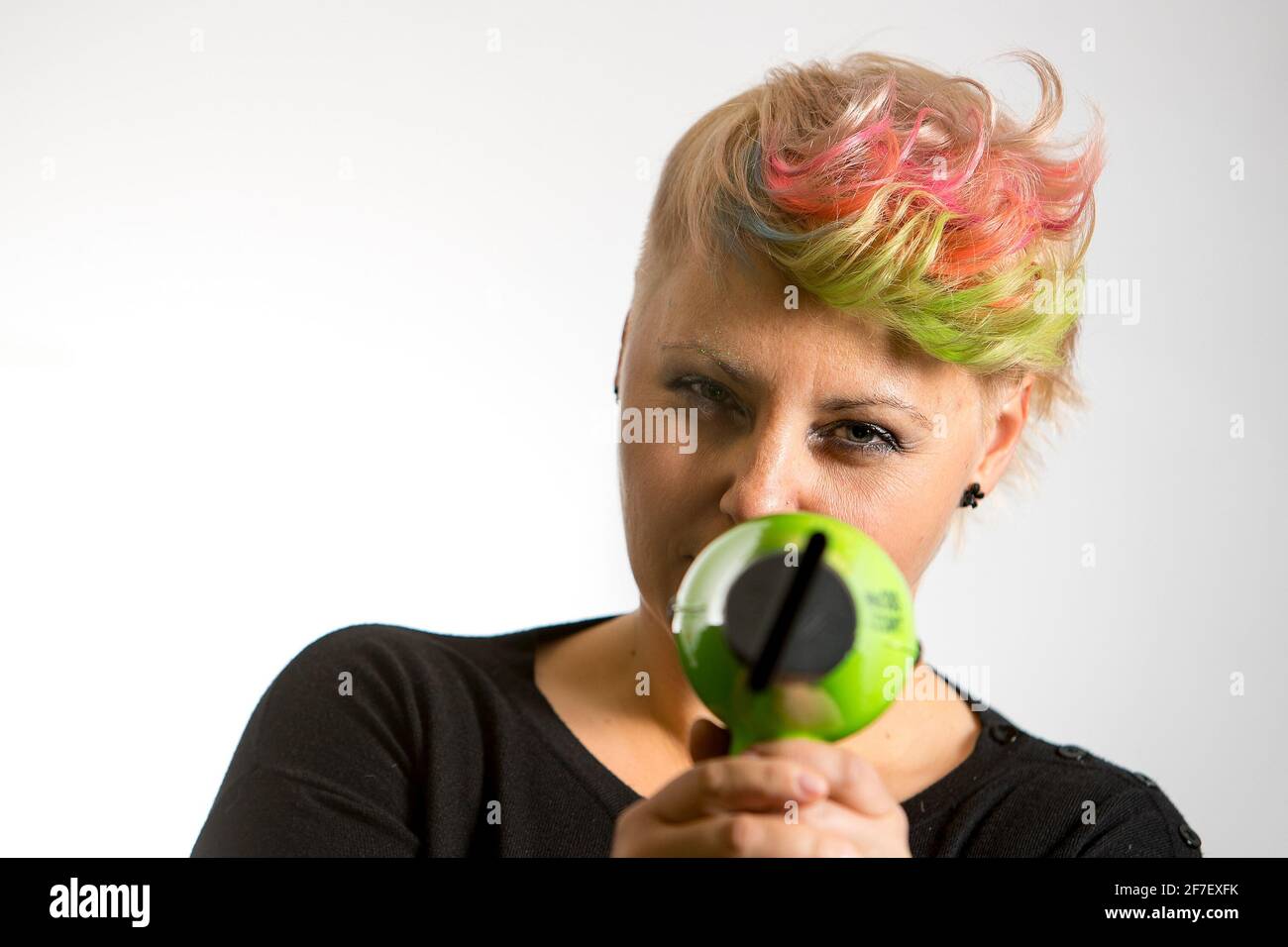 A young woman posing with a hairdryer as a gun. woman with yellow and ...
