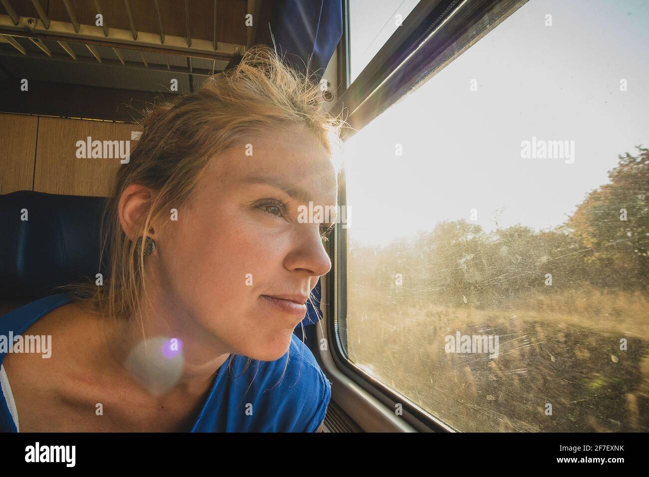 Caucasian woman using looking through a window of an older train with ...