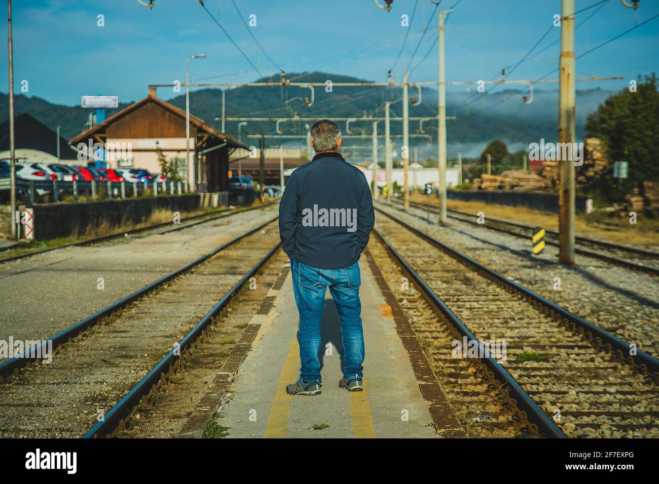 Man in jeans and jacket is waiting for a train in the early morning ...