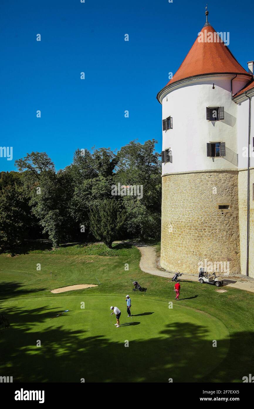 A group of golfers are playing golf in front of a prehistoric, medieval ...