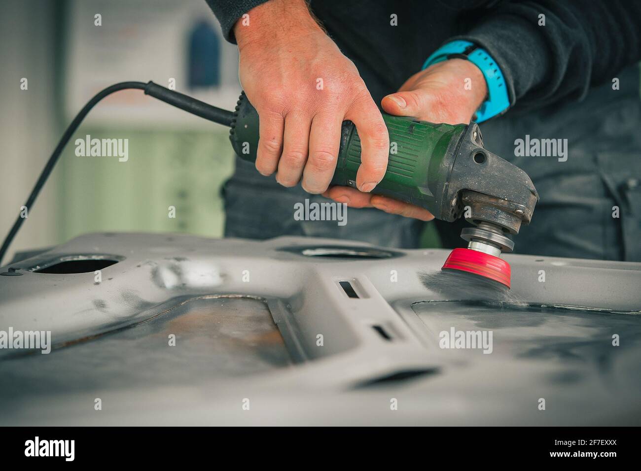 Young service man is using an angle grinder with a wire brush to clean ...