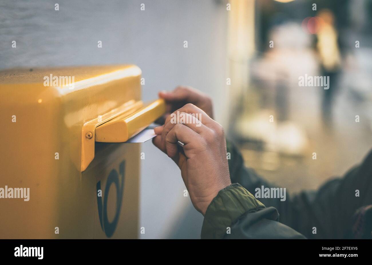Hands of a white young caucasian woman seen inserting a mail envelope ...