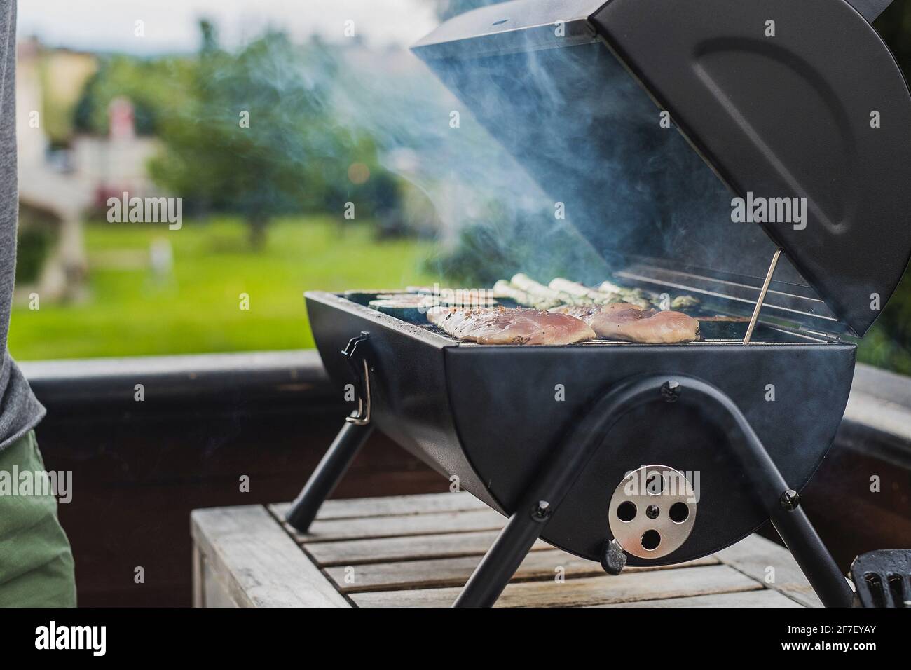 Smoke coming out of a smokestack of a small black smoker grill or ...