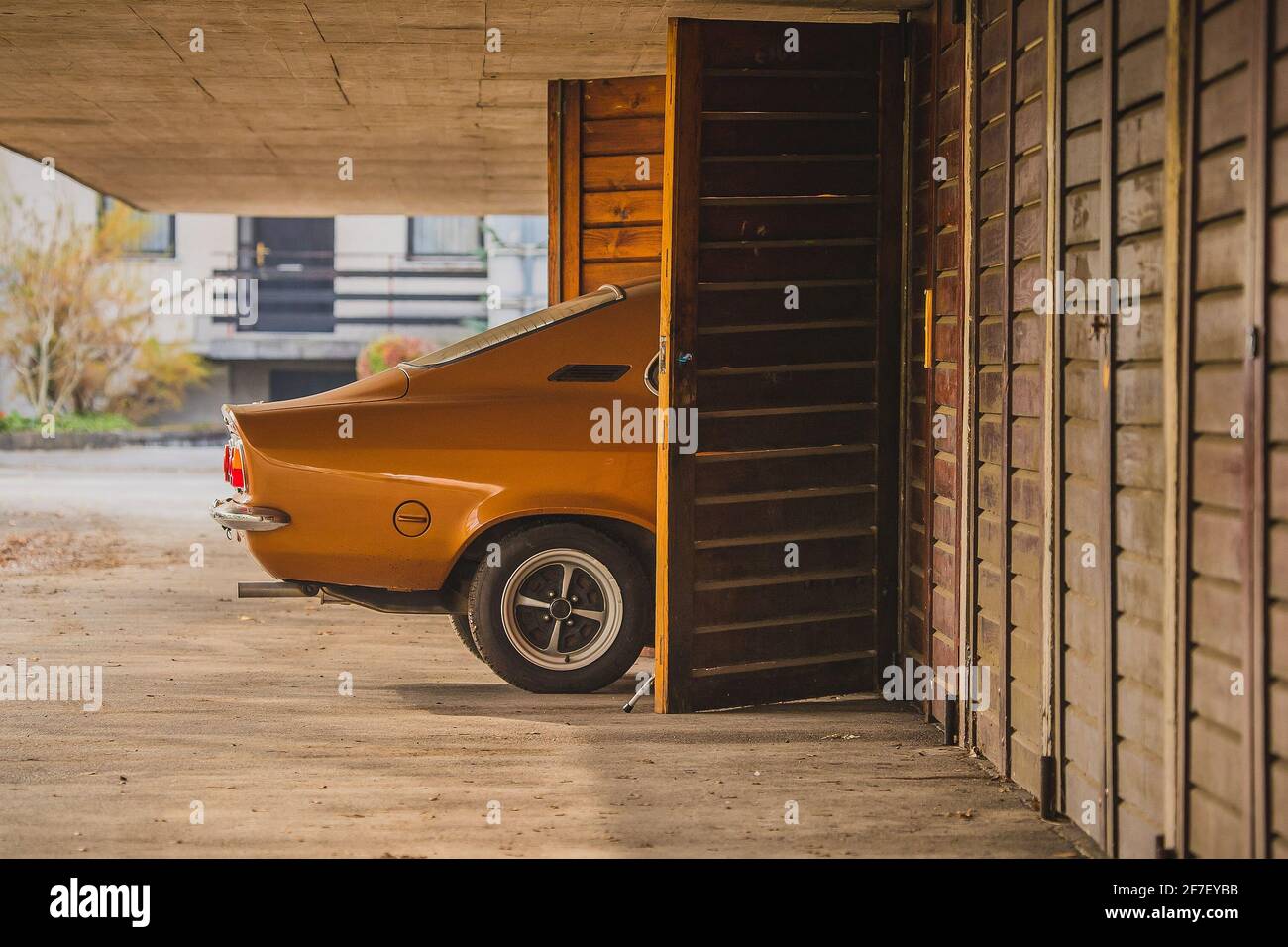 Old brown vintage car is being parked in a wooden car box parking. Rear ...