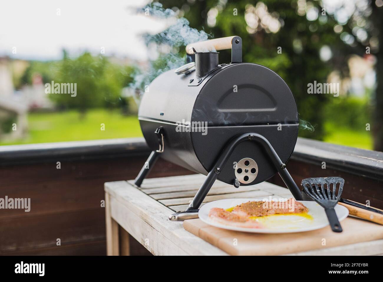 Smoke coming out of a smokestack of a small black smoker grill or ...