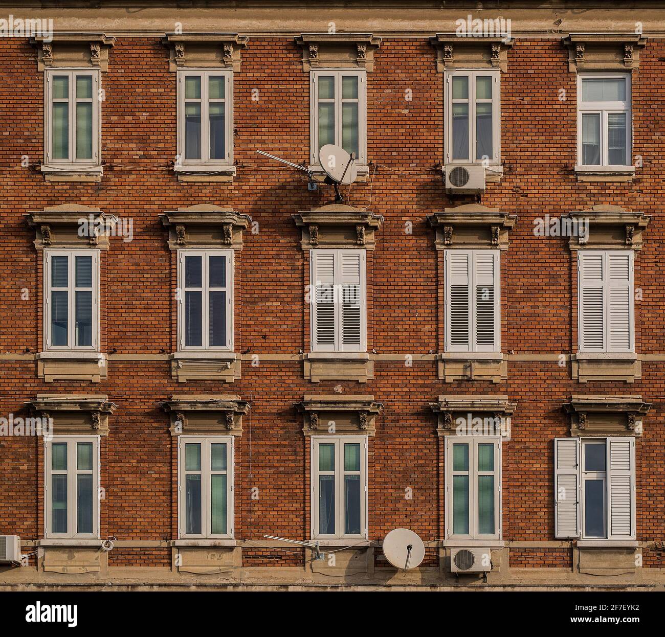 View of a brick facade with white windows. Two air conditioner units ...