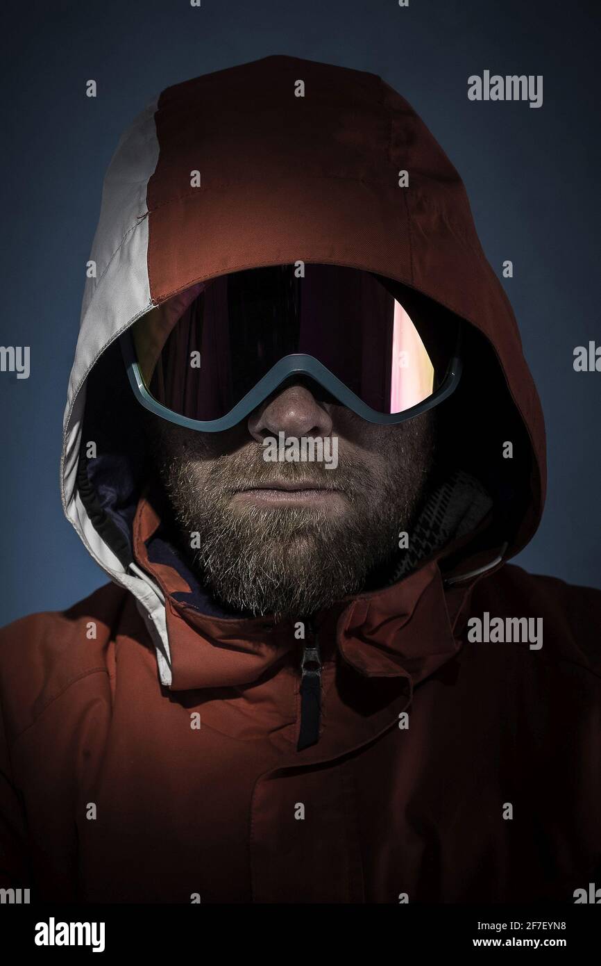 Portrait of a young man with beard, serious face, ski jacket over his ...