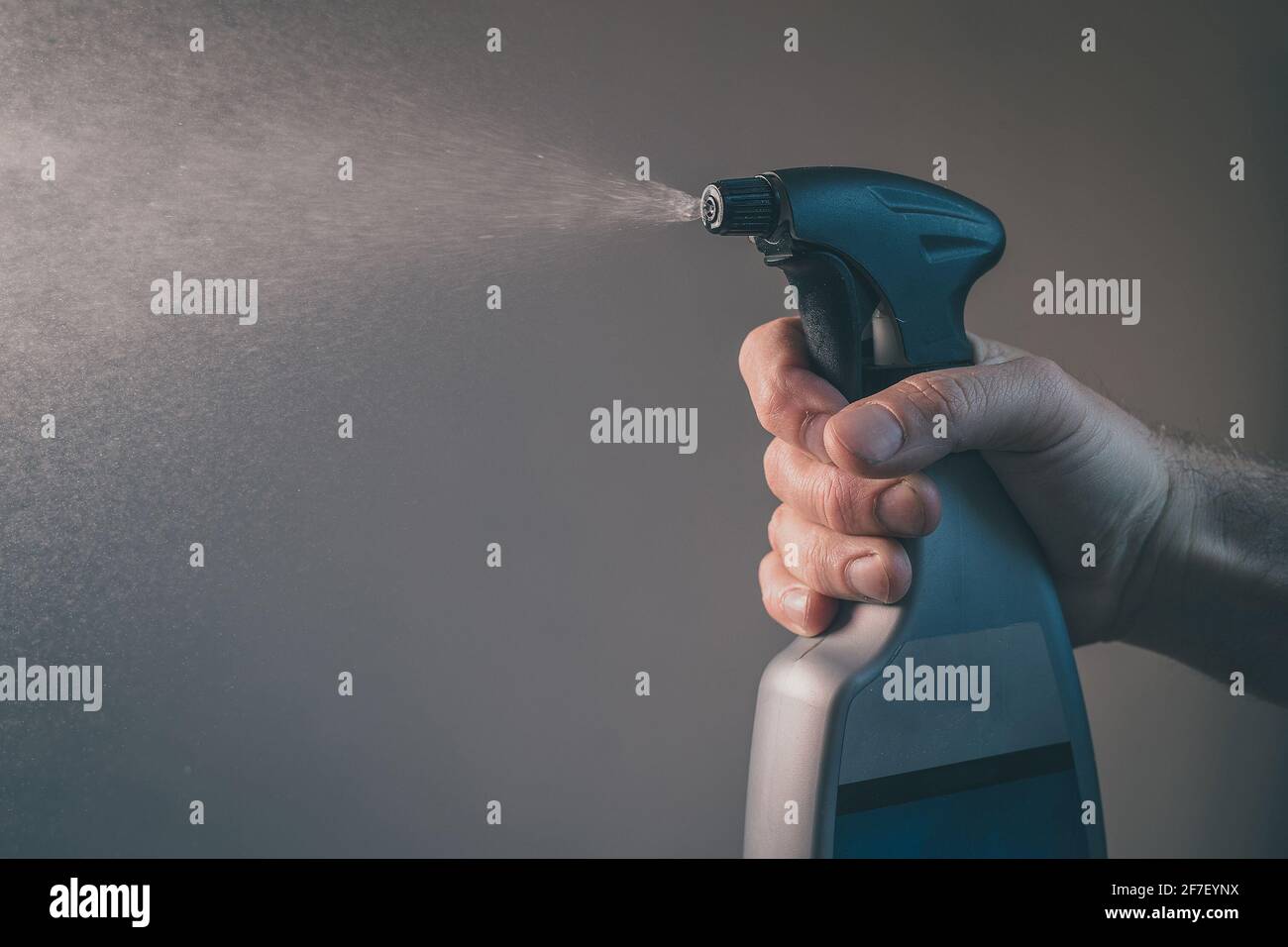 Bare hand holding a spray bottle for cleaning and operating it. Drops ...