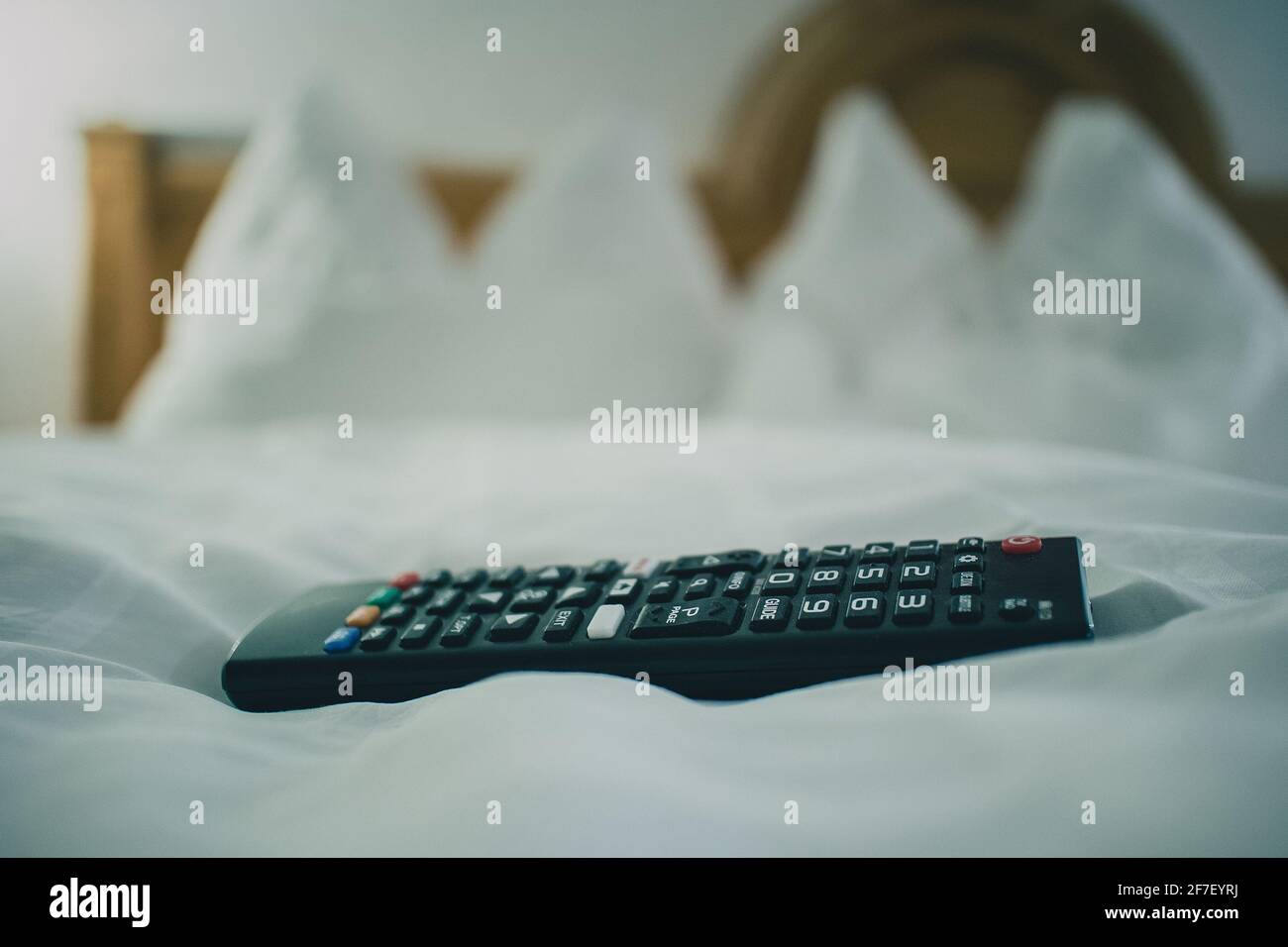 Modern television remote on a bed in a hotel. Wooden hotel room bed ...