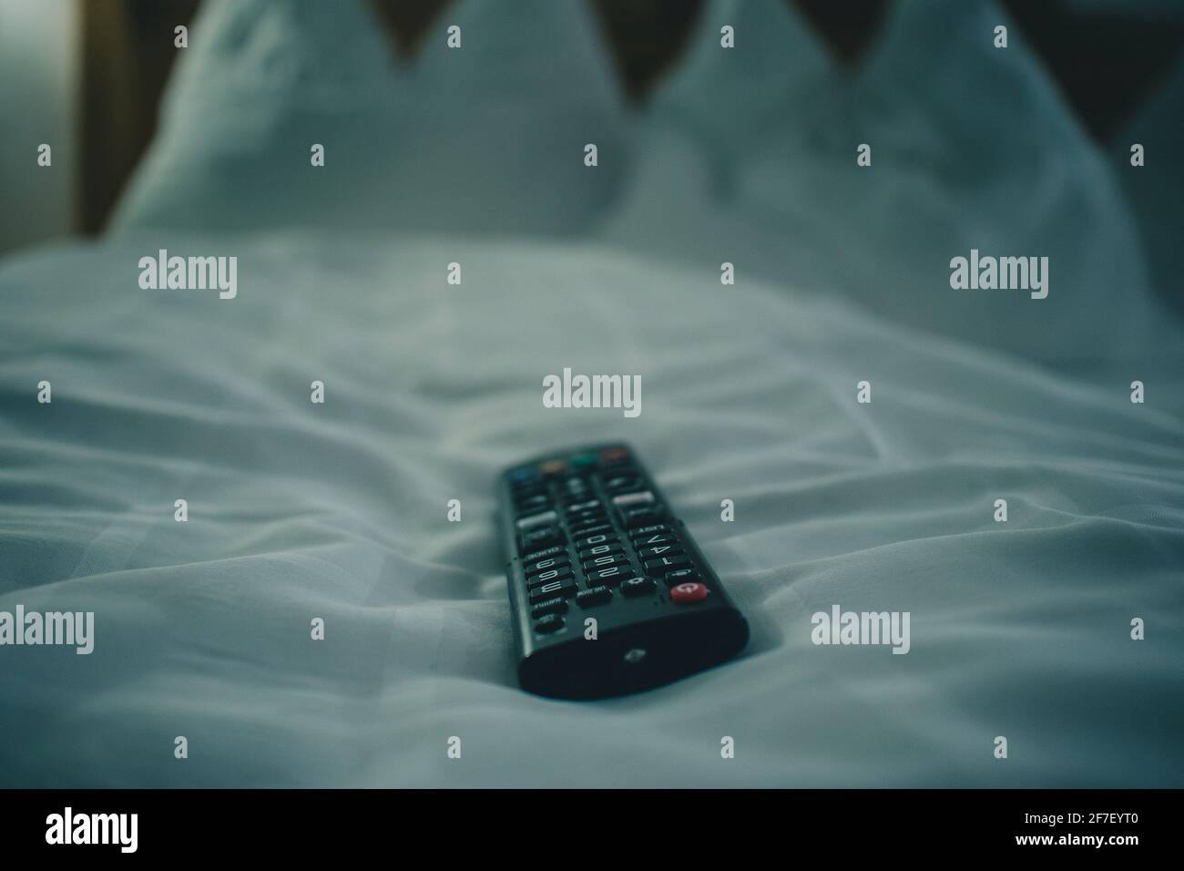 Modern television remote on a bed in a hotel. Wooden hotel room bed ...