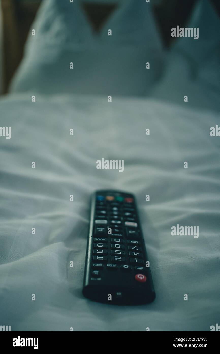 Modern television remote on a bed in a hotel. Wooden hotel room bed ...