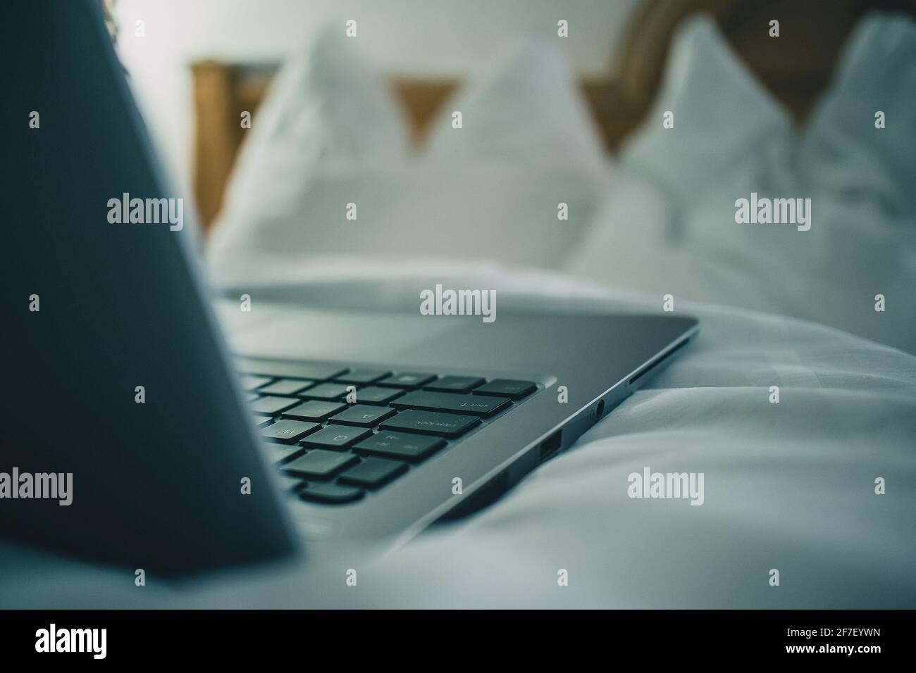 Detail view of a laptop keyboard sitting on a bed in hotel room ...