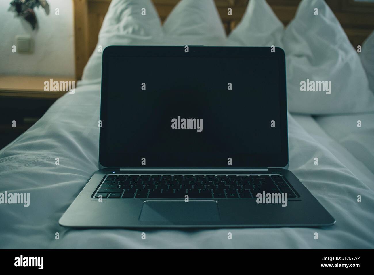 Frontal view of a laptop keyboard sitting on a bed in hotel room ...