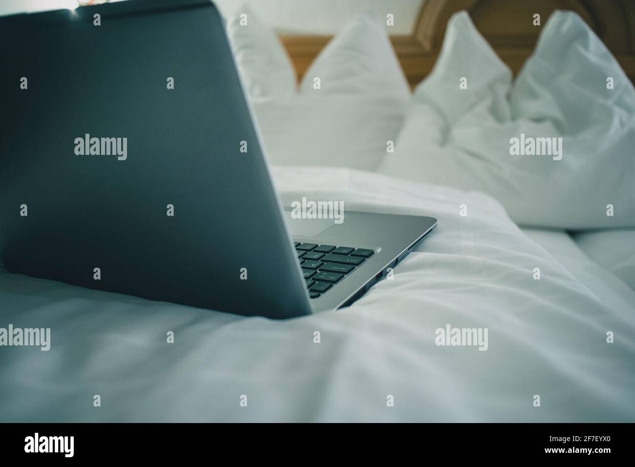 Detail view of a laptop keyboard sitting on a bed in hotel room ...