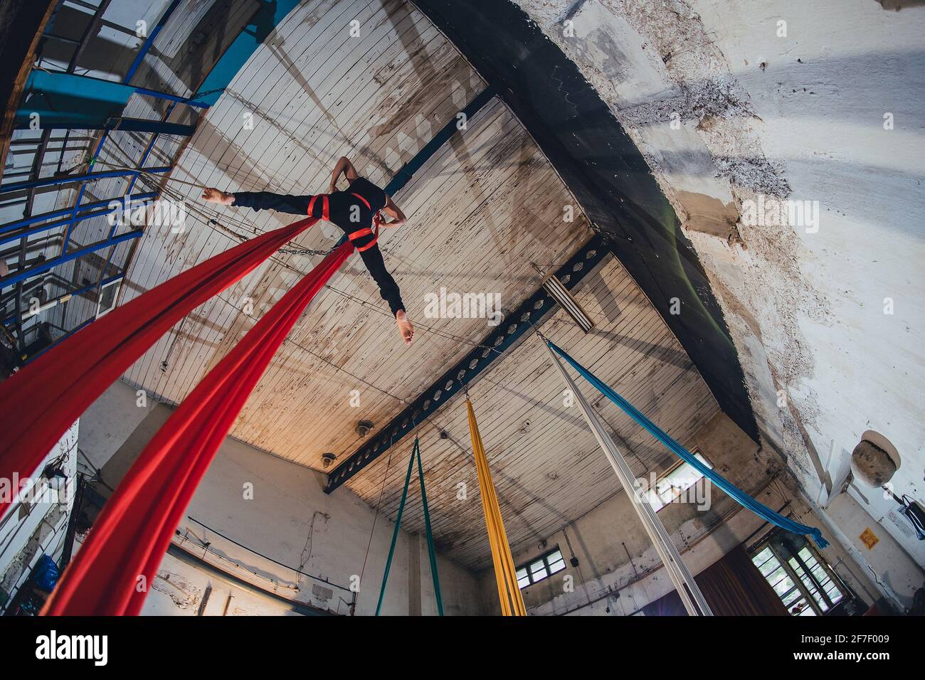 A woman aerial gymnastic dancer on silk rope performing in an industral ...