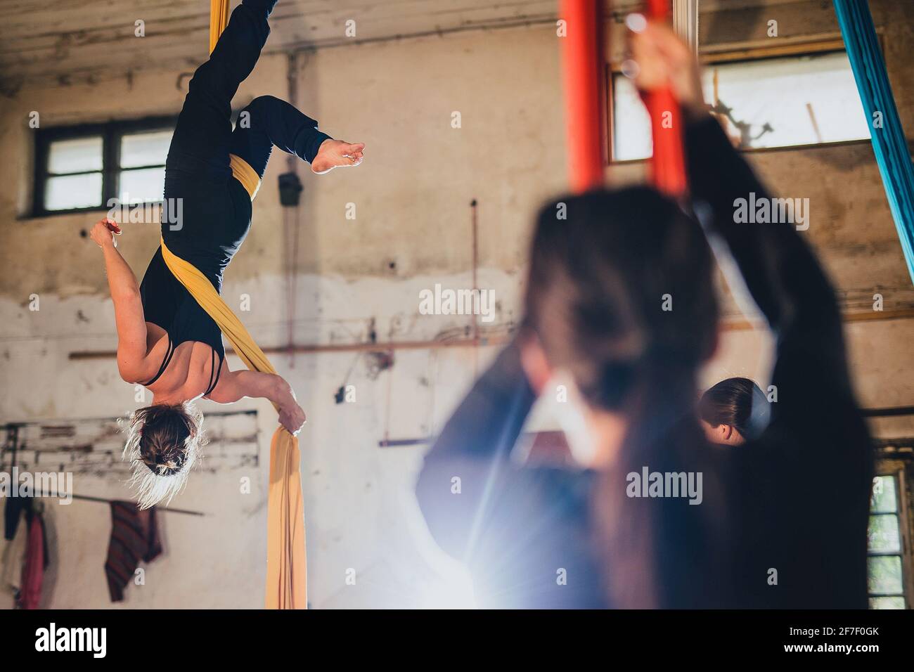 A woman aerial gymnastic dancer on silk rope performing in an industral ...