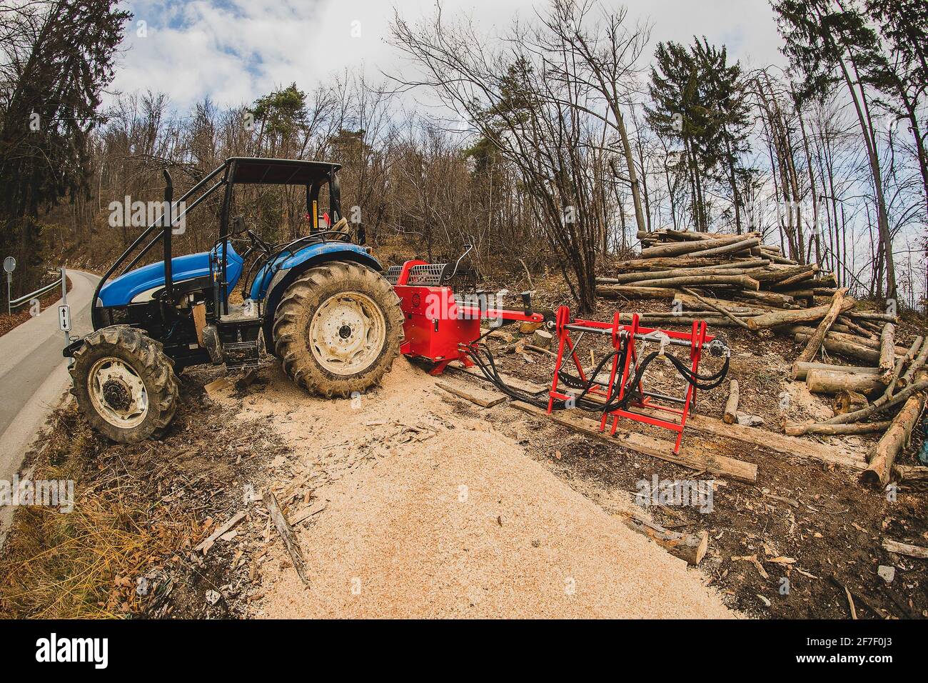 A mobile sawmill parked in a forest, connected to a tractor. Harvesting ...