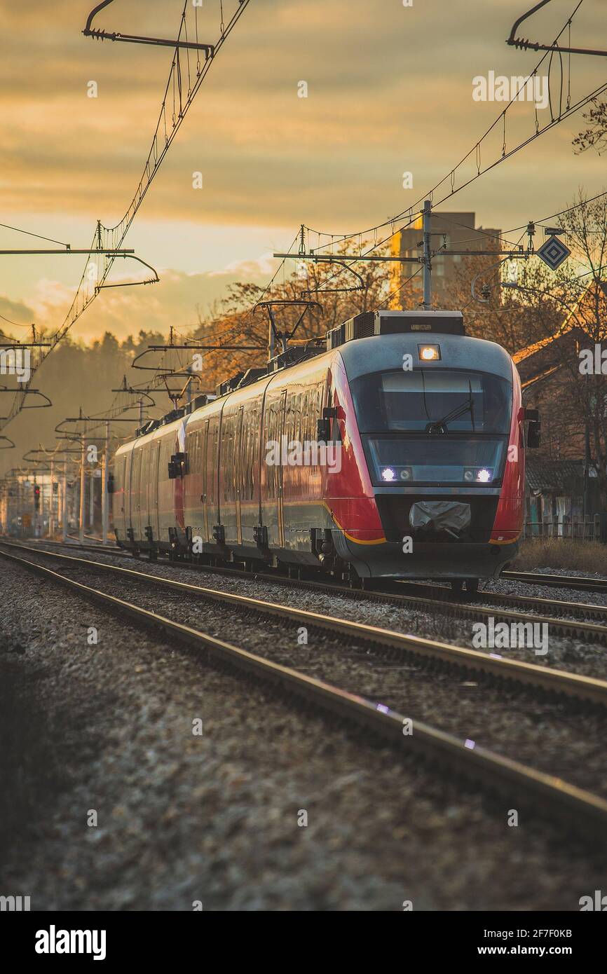 European style red passenger train of a modern type on a straight track ...
