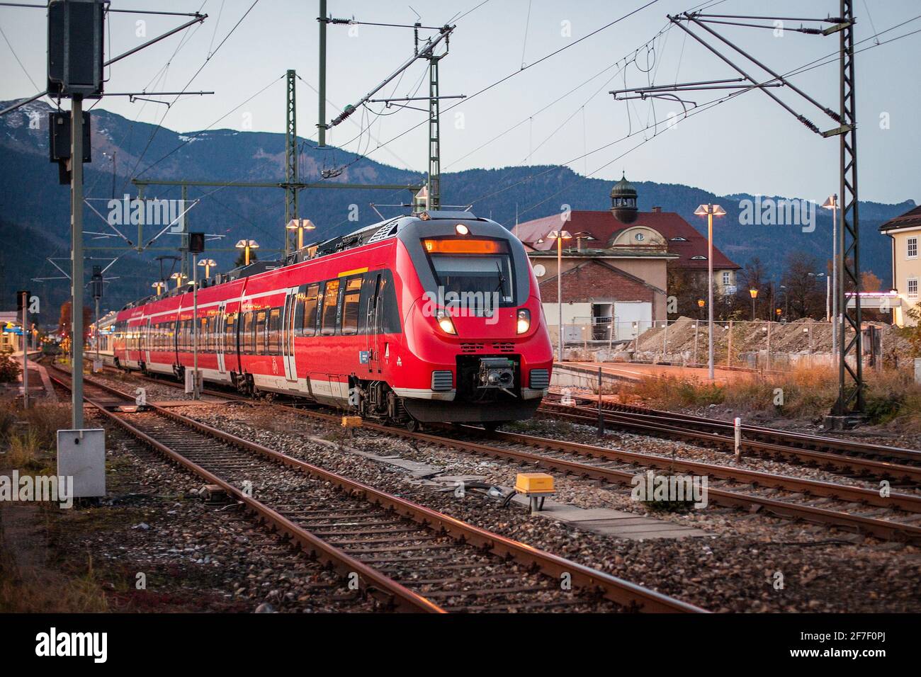 Red commuter train is entering a station of Garmisch Partenkirchen in ...