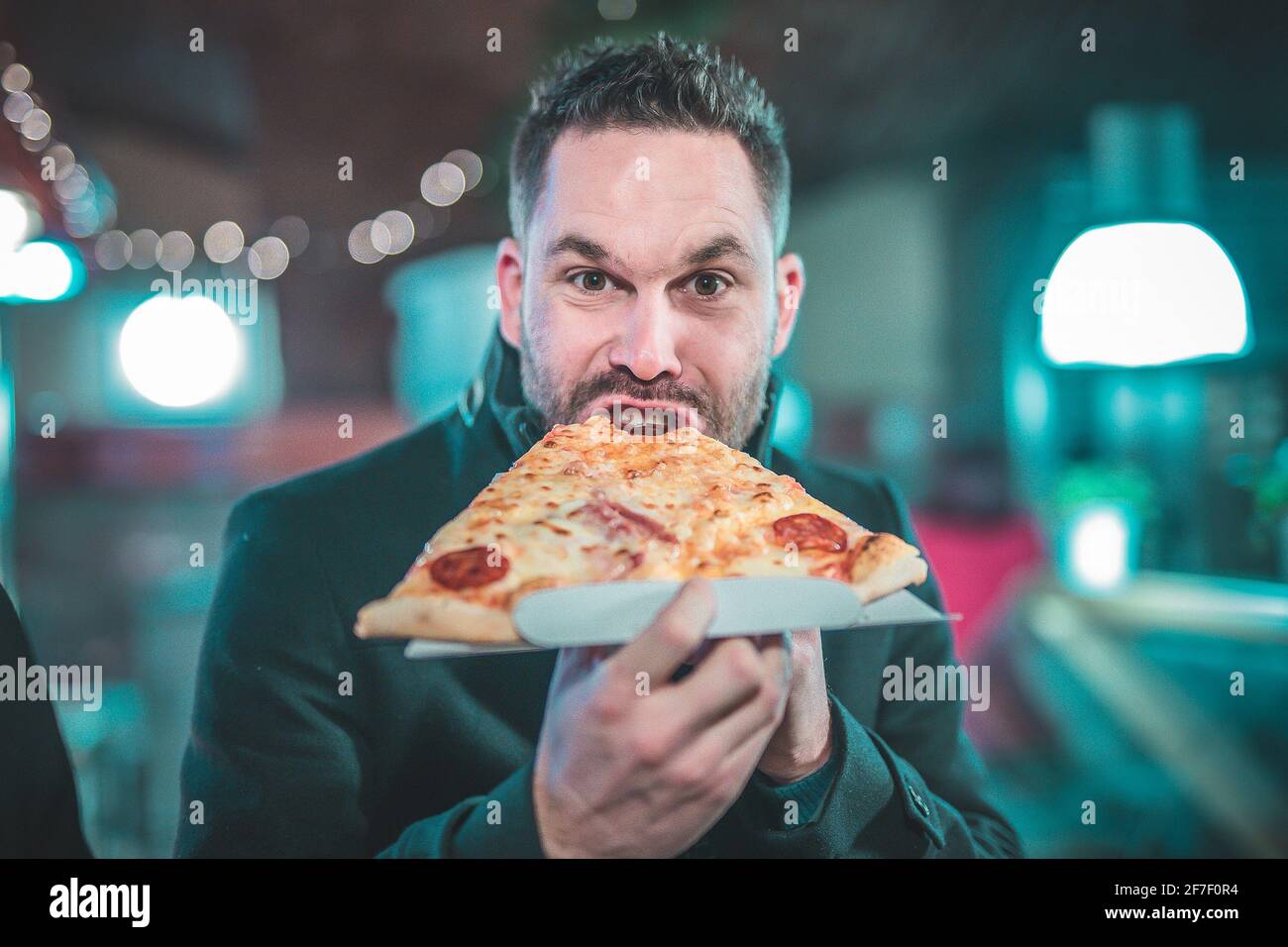 Young caucasian male with beard and fancy jacket is eating a slice of ...