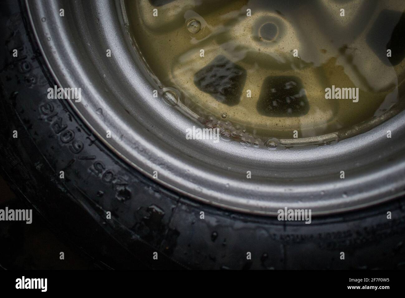 A mechanic is testng a car wheel for air leak with submerging or diving ...