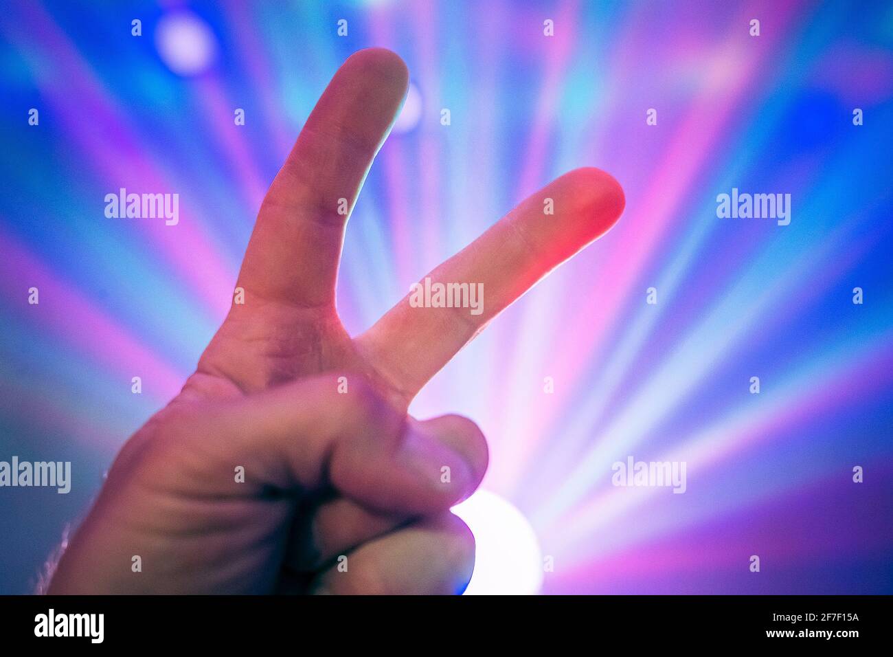 Hand of a person is seen holding a V sign or victory sign on a party ...