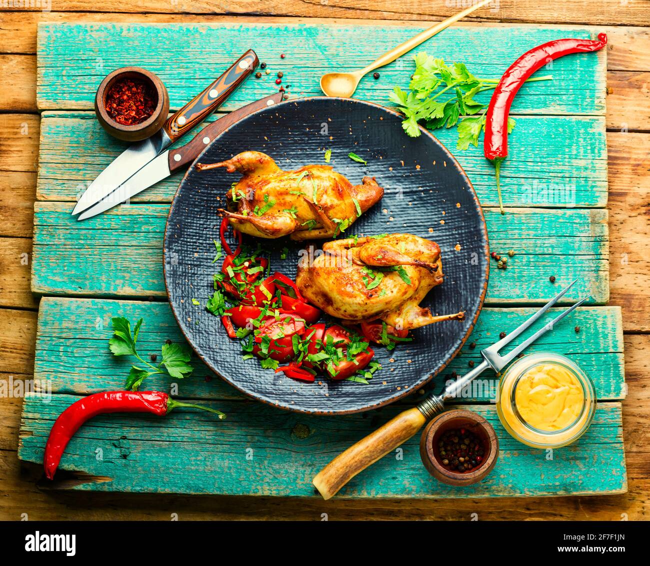 Roasted whole quails and spring vegetable salad on rustic wooden table ...