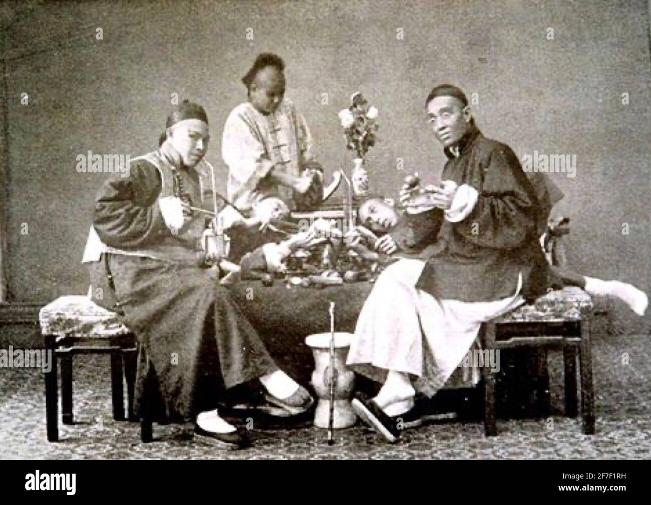 Early photograph of Chinese opium smokers. Two adults in the foreground ...