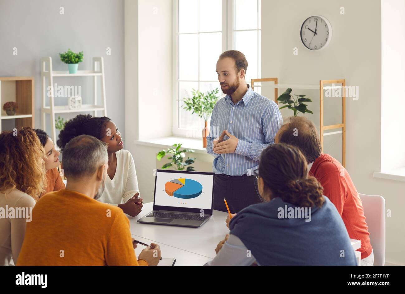 Team leader making presentation in group meeting using pie charts on ...