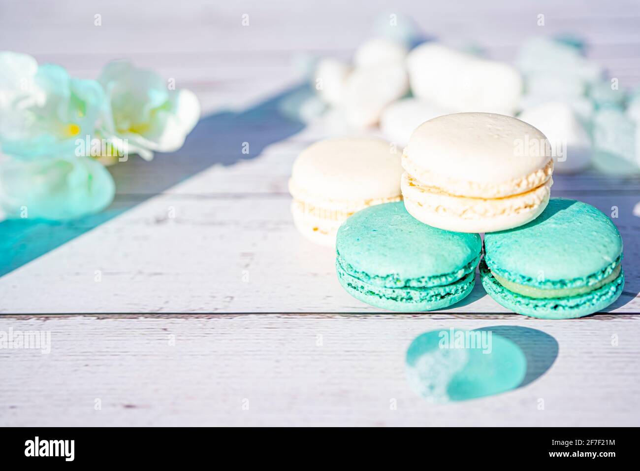 Selective focus. Turquoise and white macarons on light wooden ...