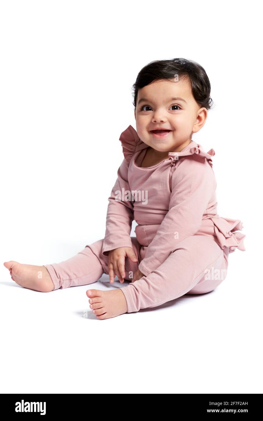 Side view of lovely baby girl in cute pink outfit smiling with mouth ...