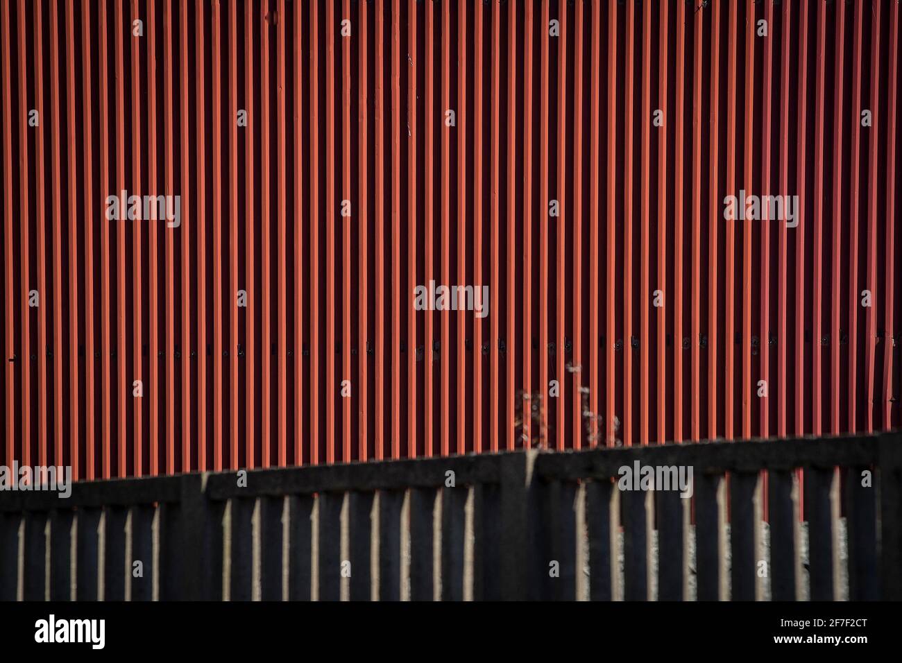 Red metal wall texture of a factory, with a concrete wall in front of ...