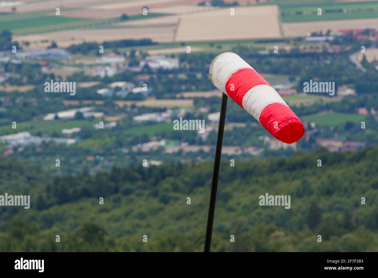 Red and white windsock measuring stormy windy weather at hill ...