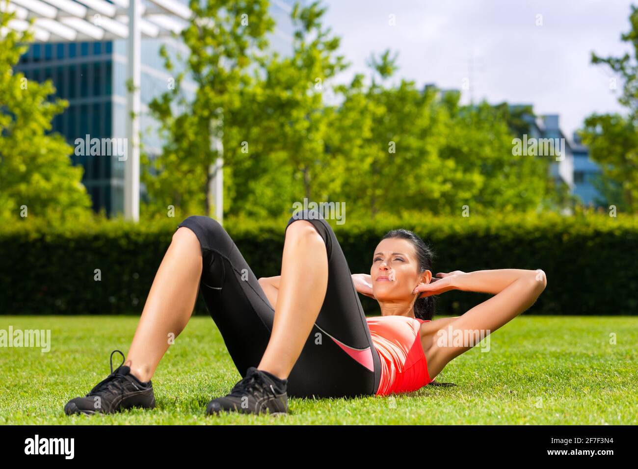 Urban sports - young woman is doing warming up and sit-ups before ...