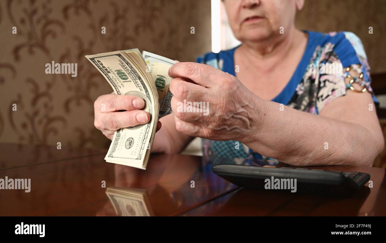 Elderly woman counts banknotes bills dollars leads budget checks money ...