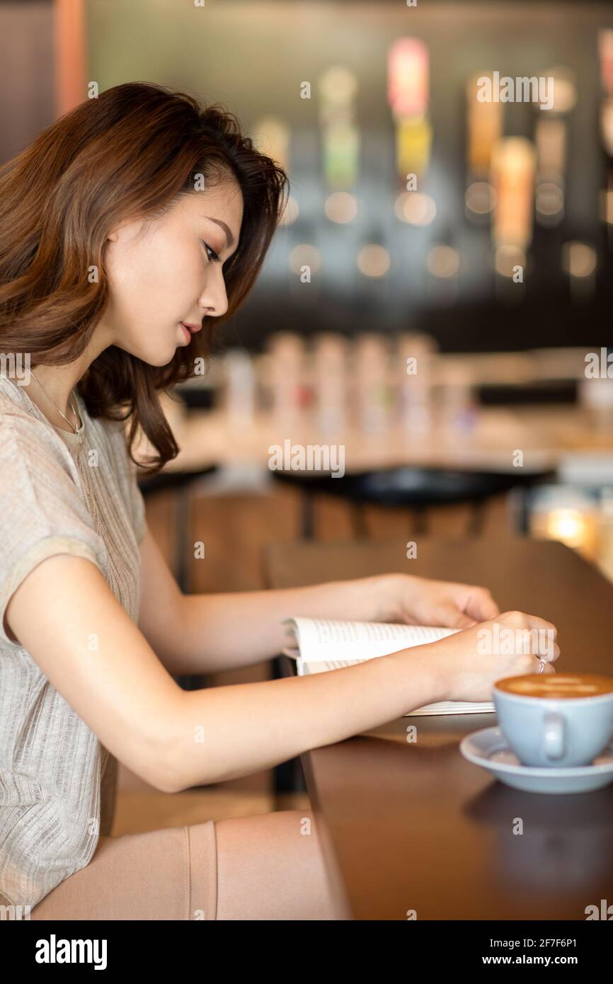 Elegant woman reading book in cafe Stock Photo - Alamy