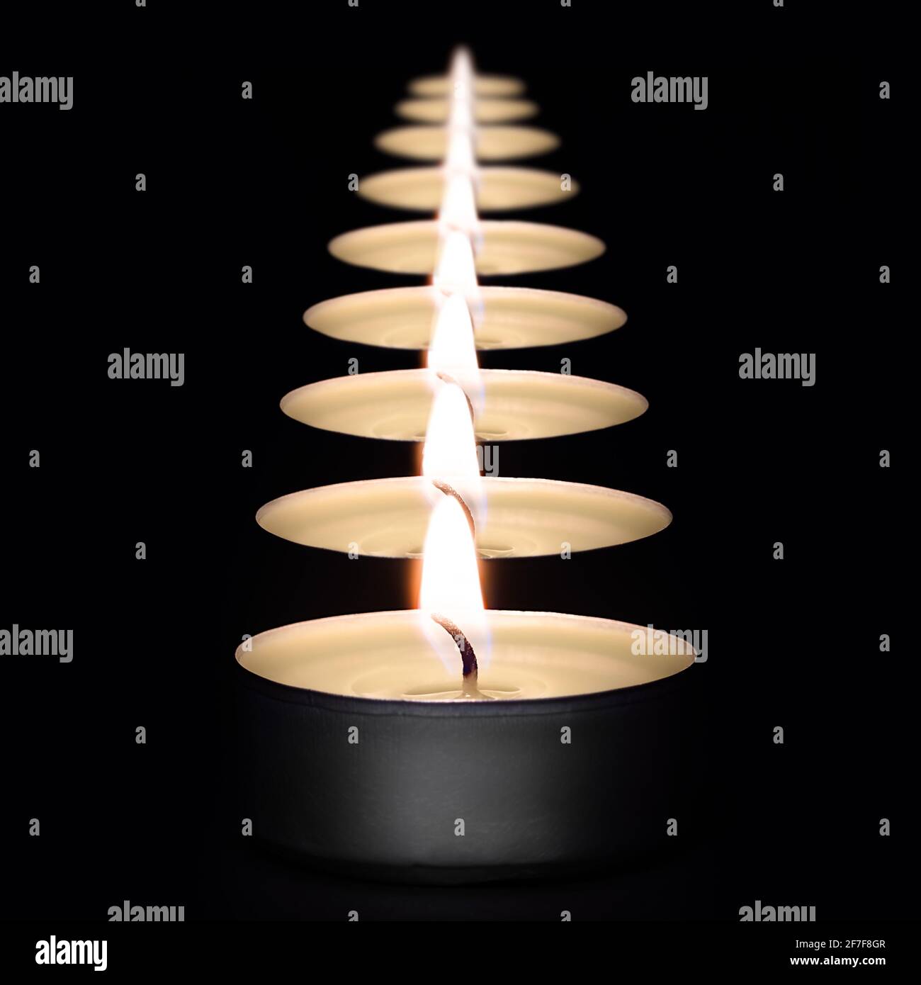A row of burning candles on a dark background with a flare in the ...