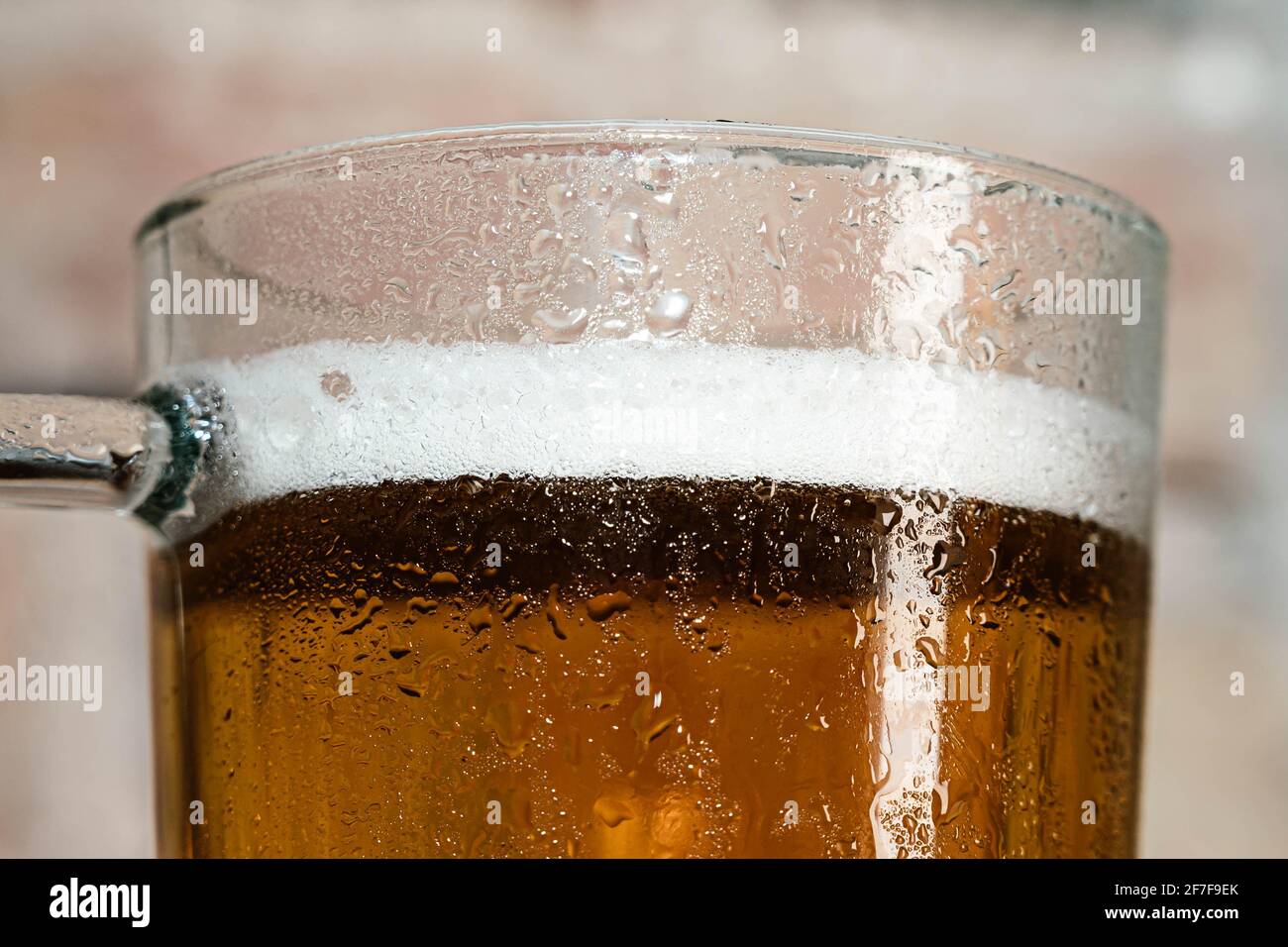Glass pint of beer with water drops on wood table isolated with brick ...