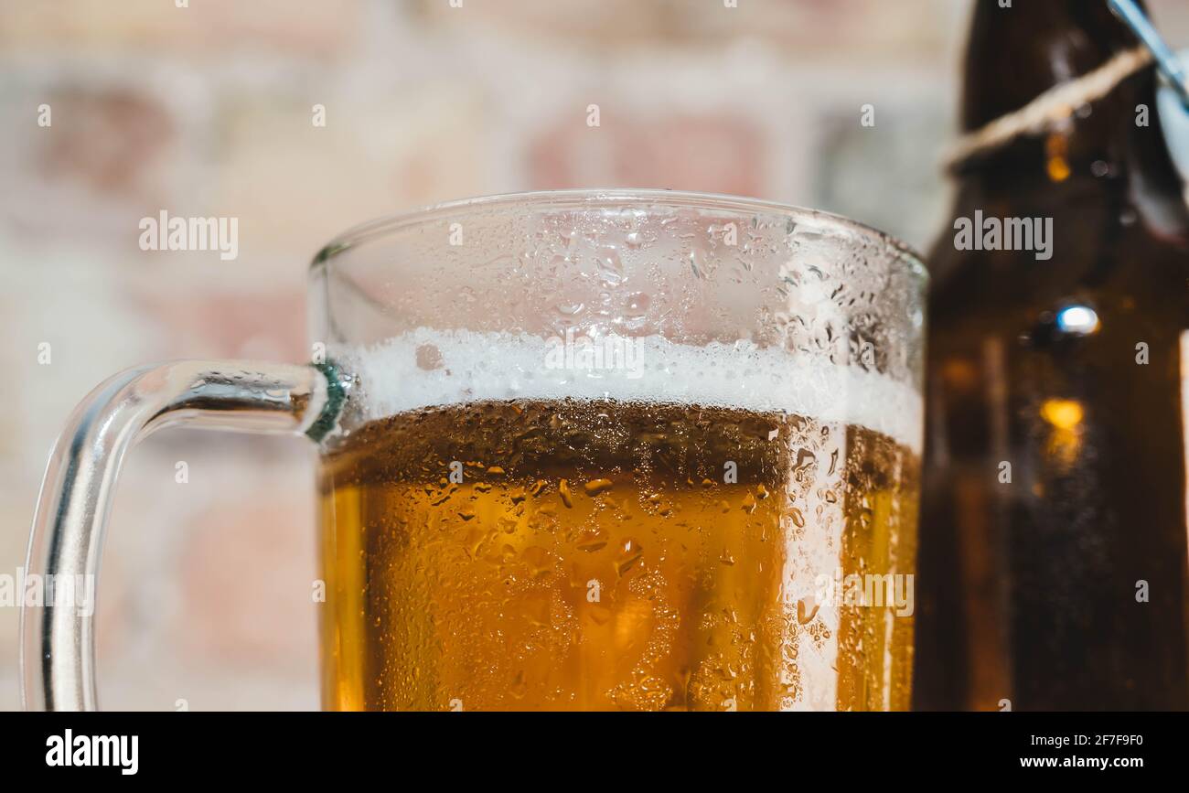 Glass pint with water drops and bottle of beer on wood table isolated ...