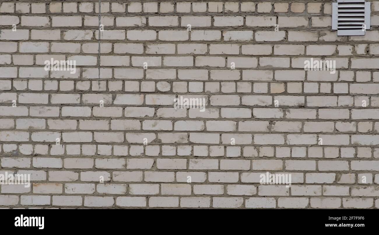 White brick wall with ventilation grate. The exterior of the building ...